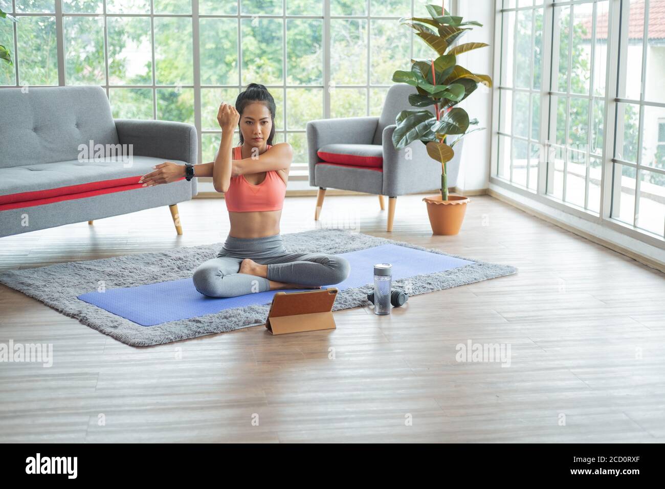 Training at home. Young asian woman doing body stretching while online ...