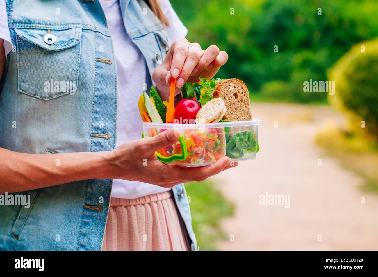 Healthy food concept: Young woman eating from lunch box filled with ...