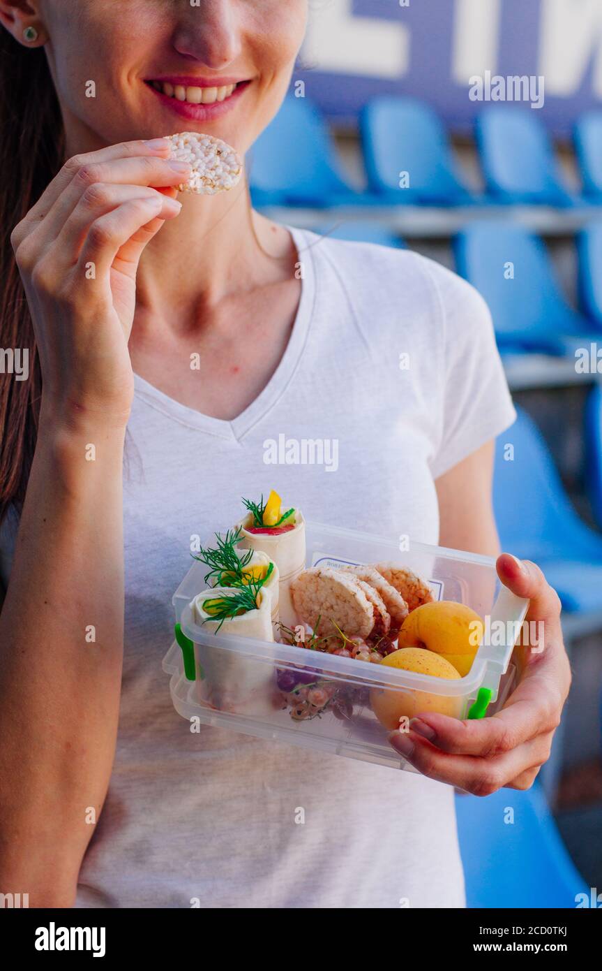 Healthy food concept: Young woman eating from lunch box filled with ...
