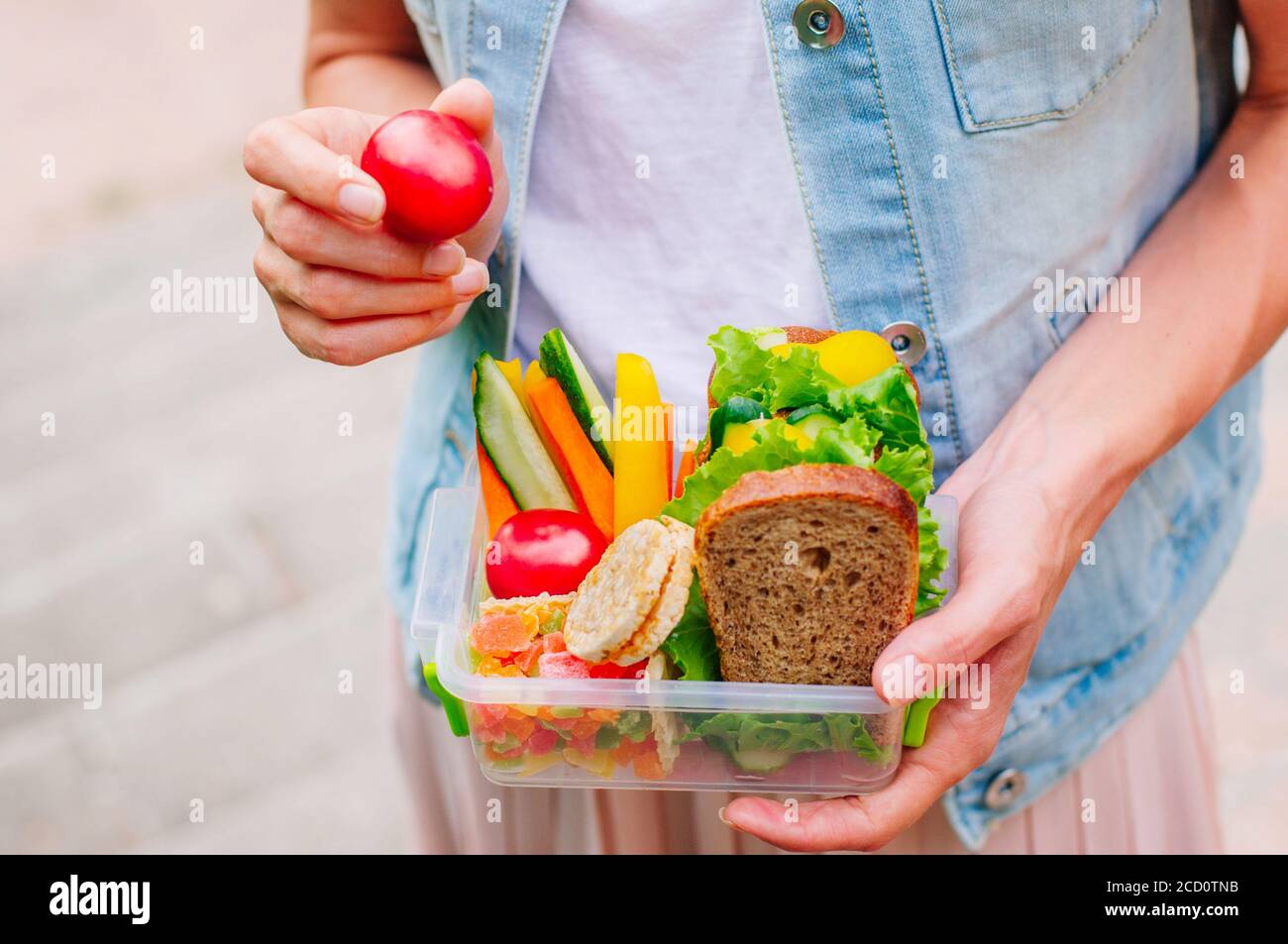 Healthy food concept: Young woman eating from lunch box filled with ...