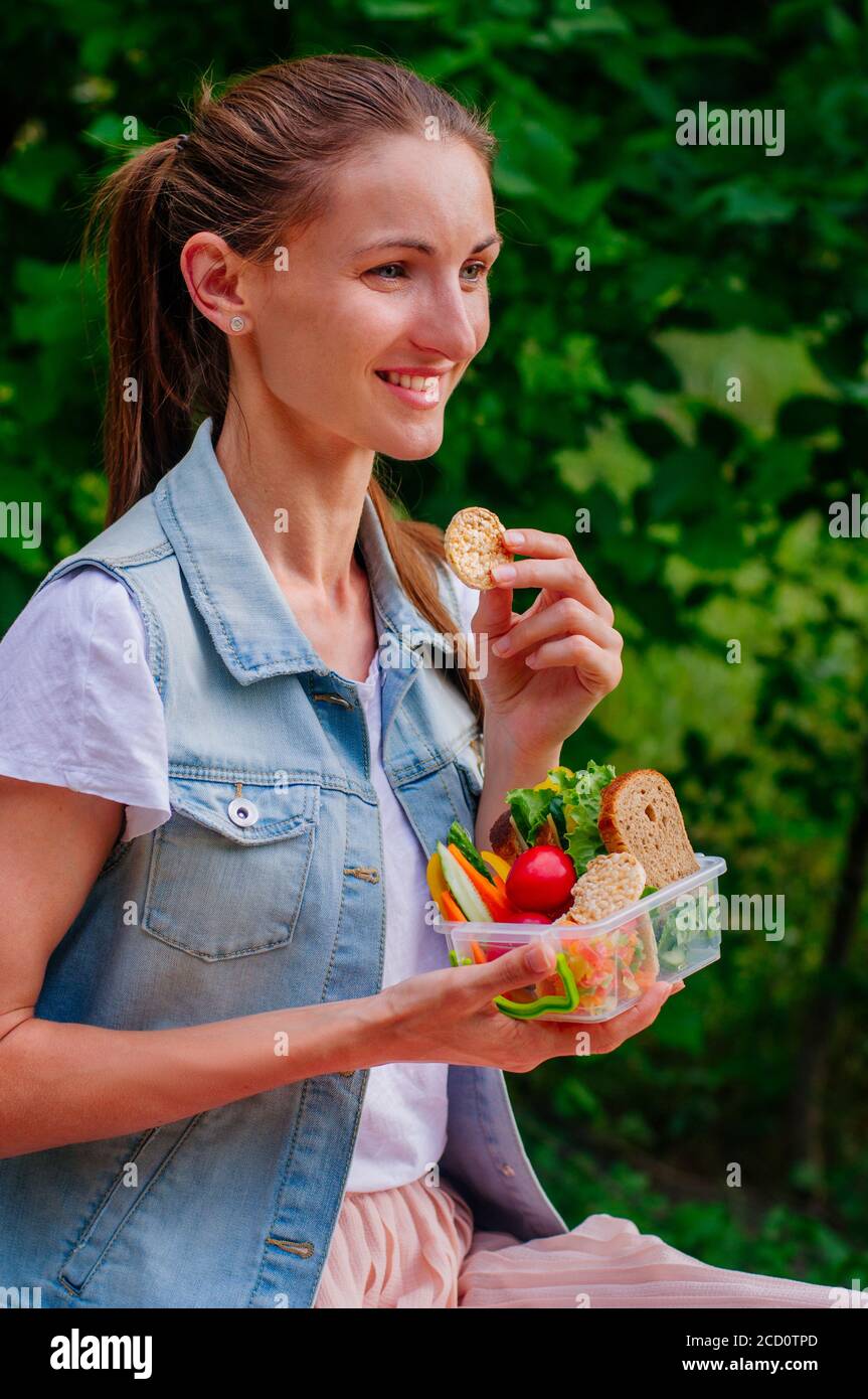 Healthy food concept: Young woman eating from lunch box filled with ...