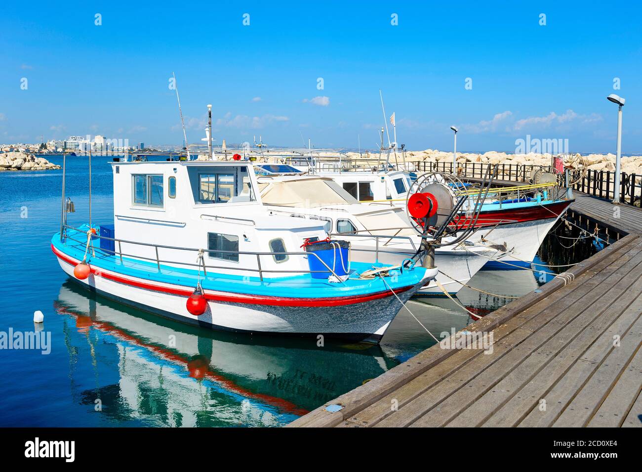 White motorboats reflecting in water, wooden pier, marina of Larnaca in ...