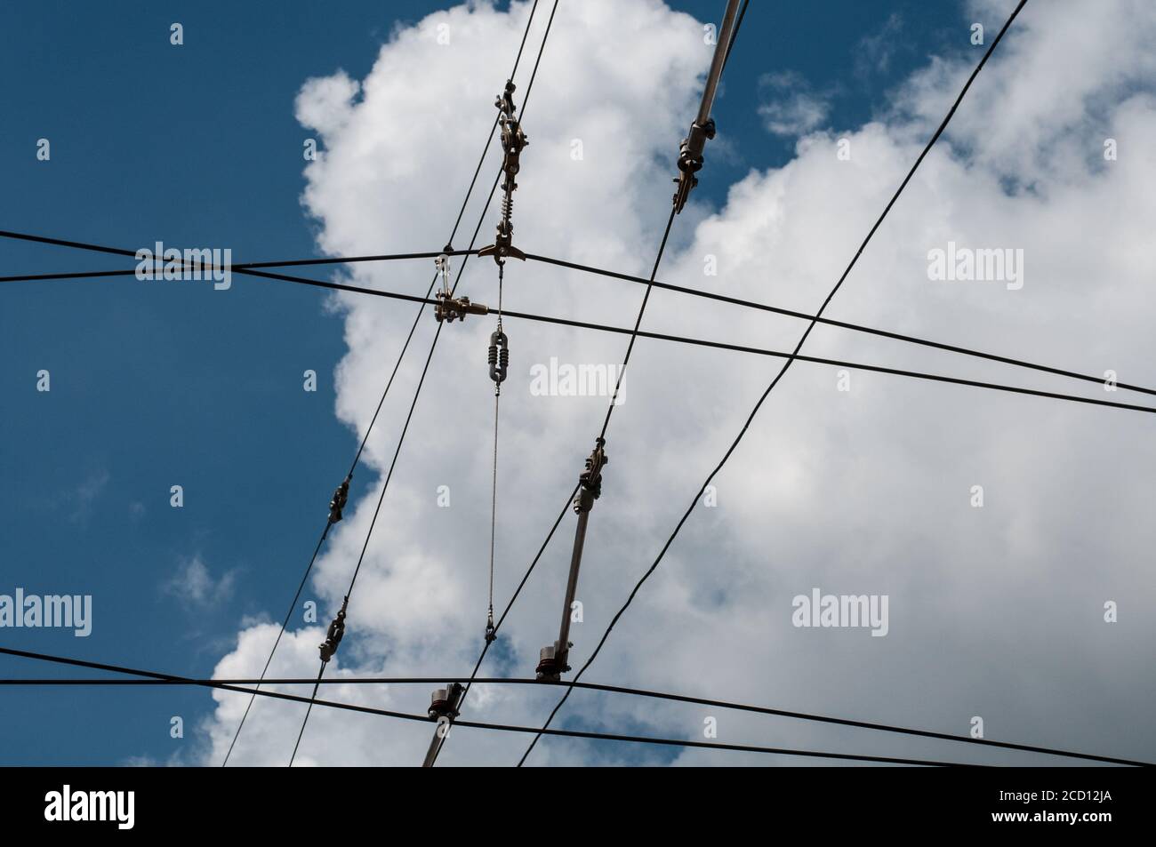 crossing power lines of a tramway with white clouds at blue sky in ...