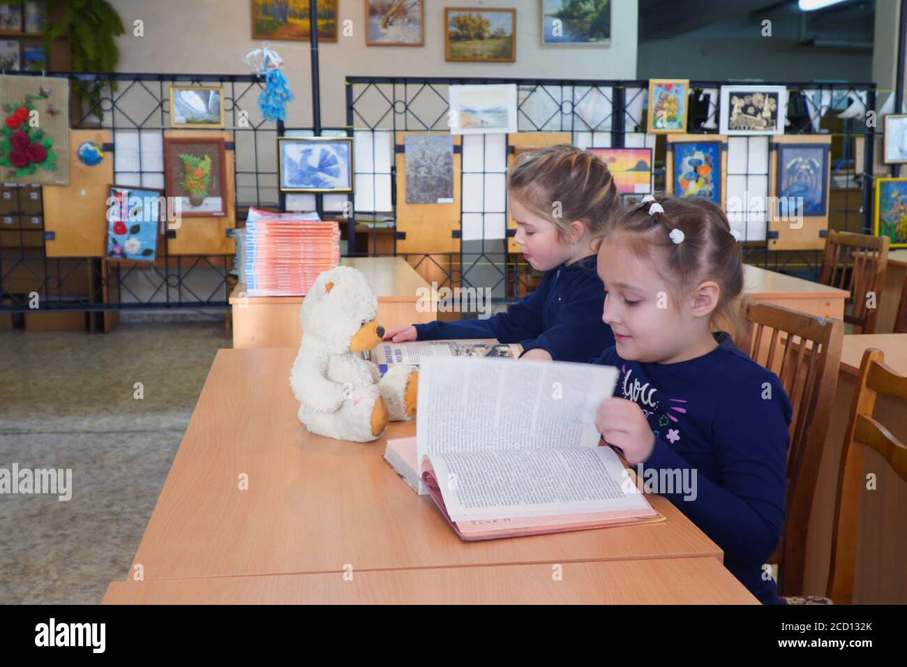 Elementary school girls at the Desk reading books Stock Photo - Alamy
