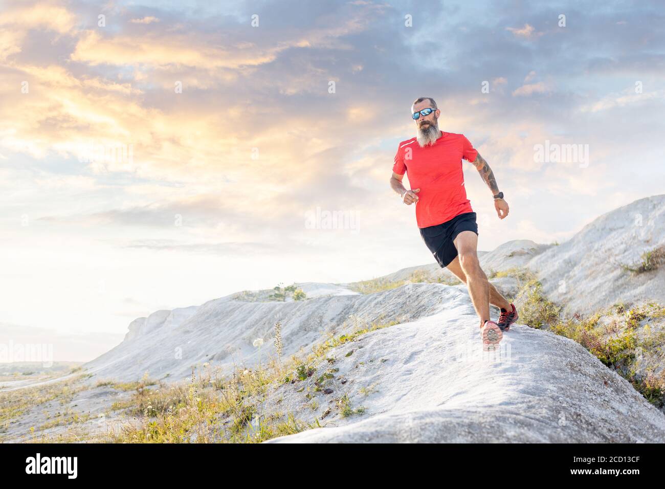 Bearded runner man jumping from the hill on trail running cross. Mature ...
