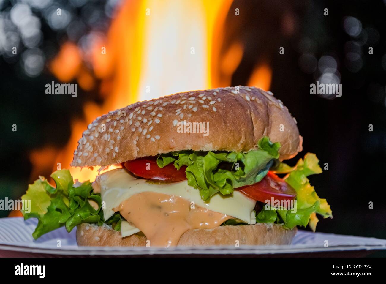 Classic tasty and unhealthy hamburger in front of fire flame. Gain ...
