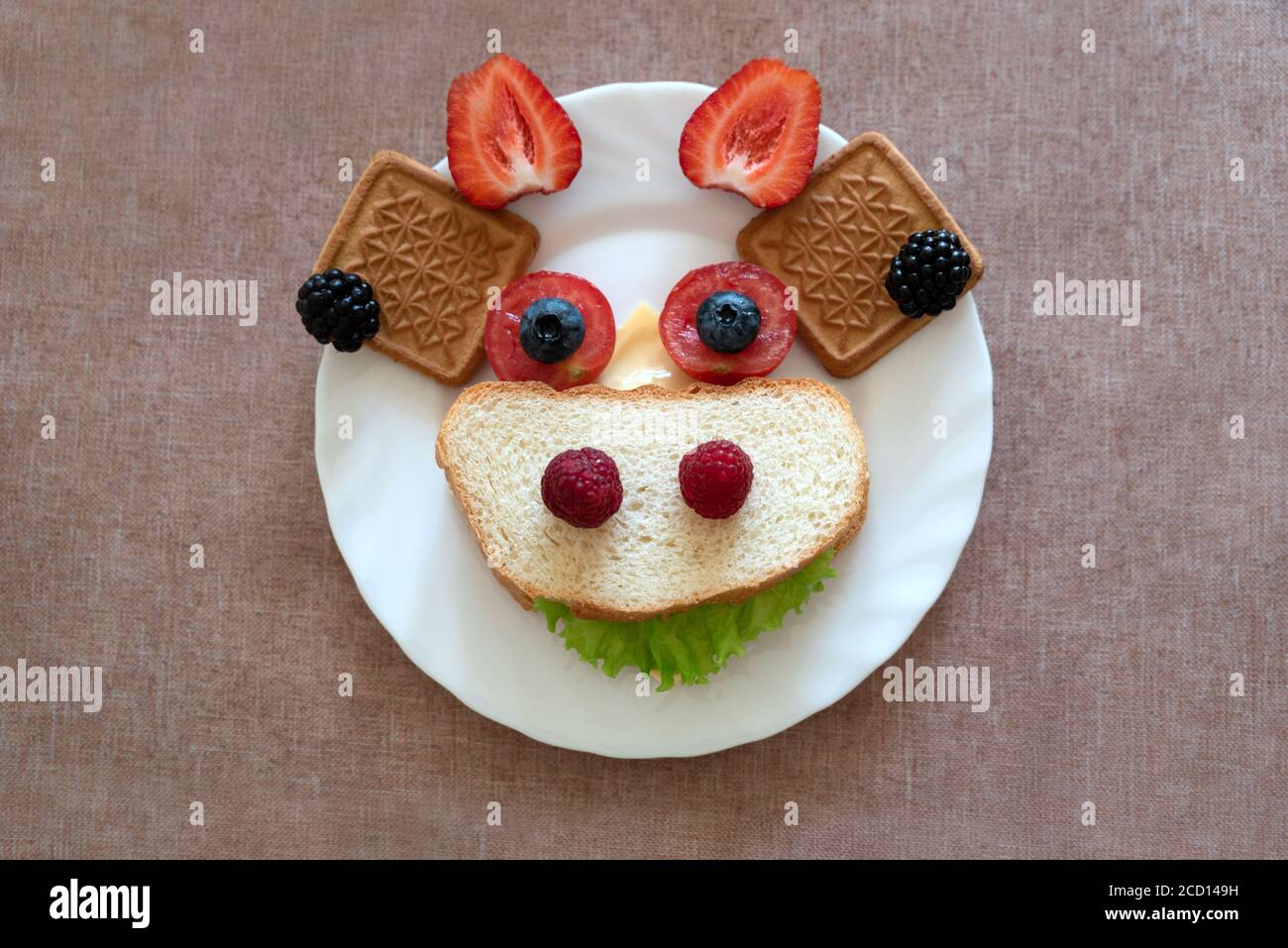 Cute cow shaped sandwich with cheese and berries. Top view. Kid food ...