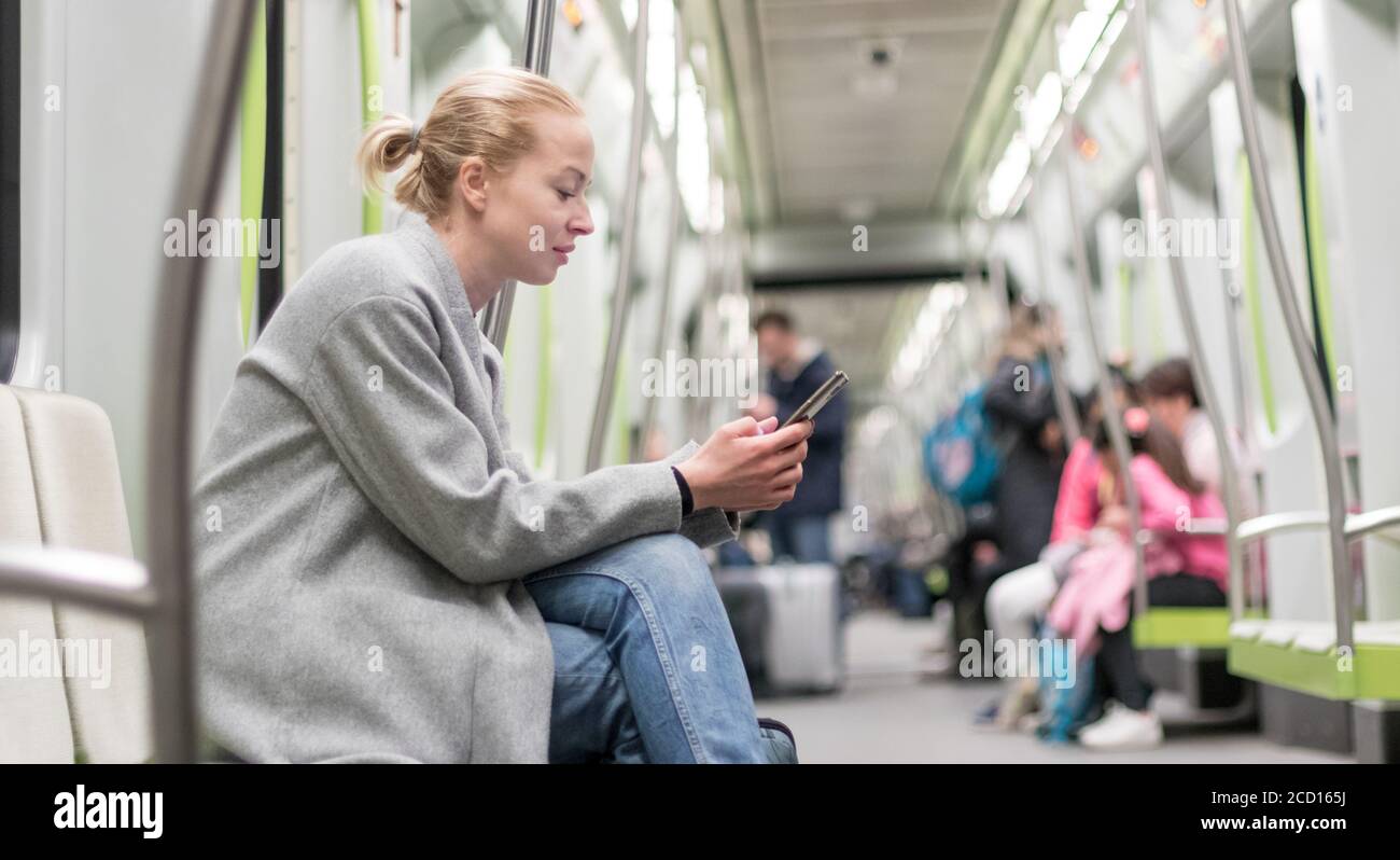 Portrait of lovely girl typing message on mobile phone in almost empty ...