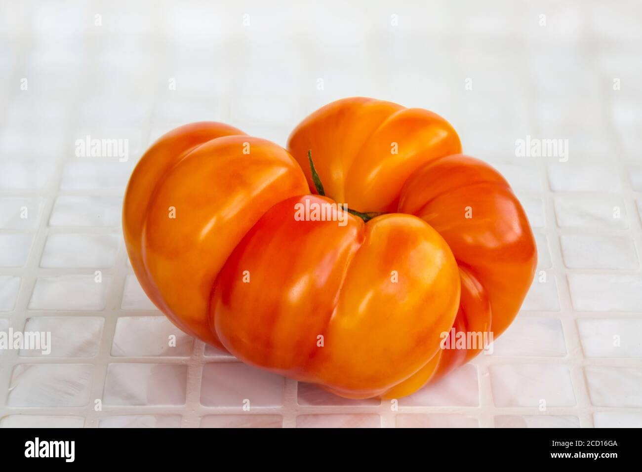 Close-up of orange, oddly shaped heirloom tomato shifting from golden ...
