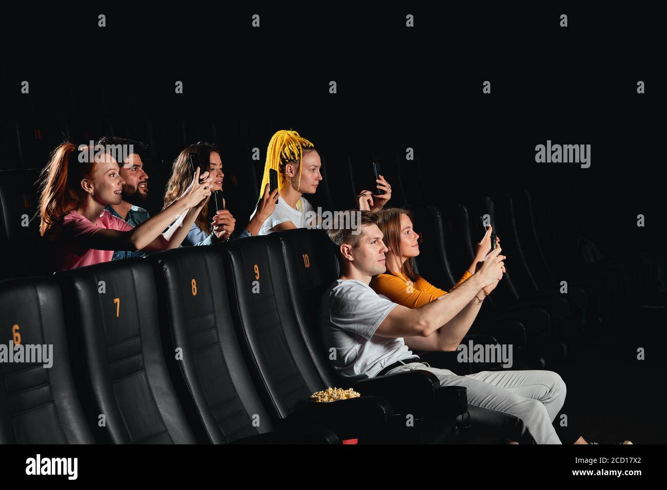 audience taking a photo while watching the performance. side view photo ...