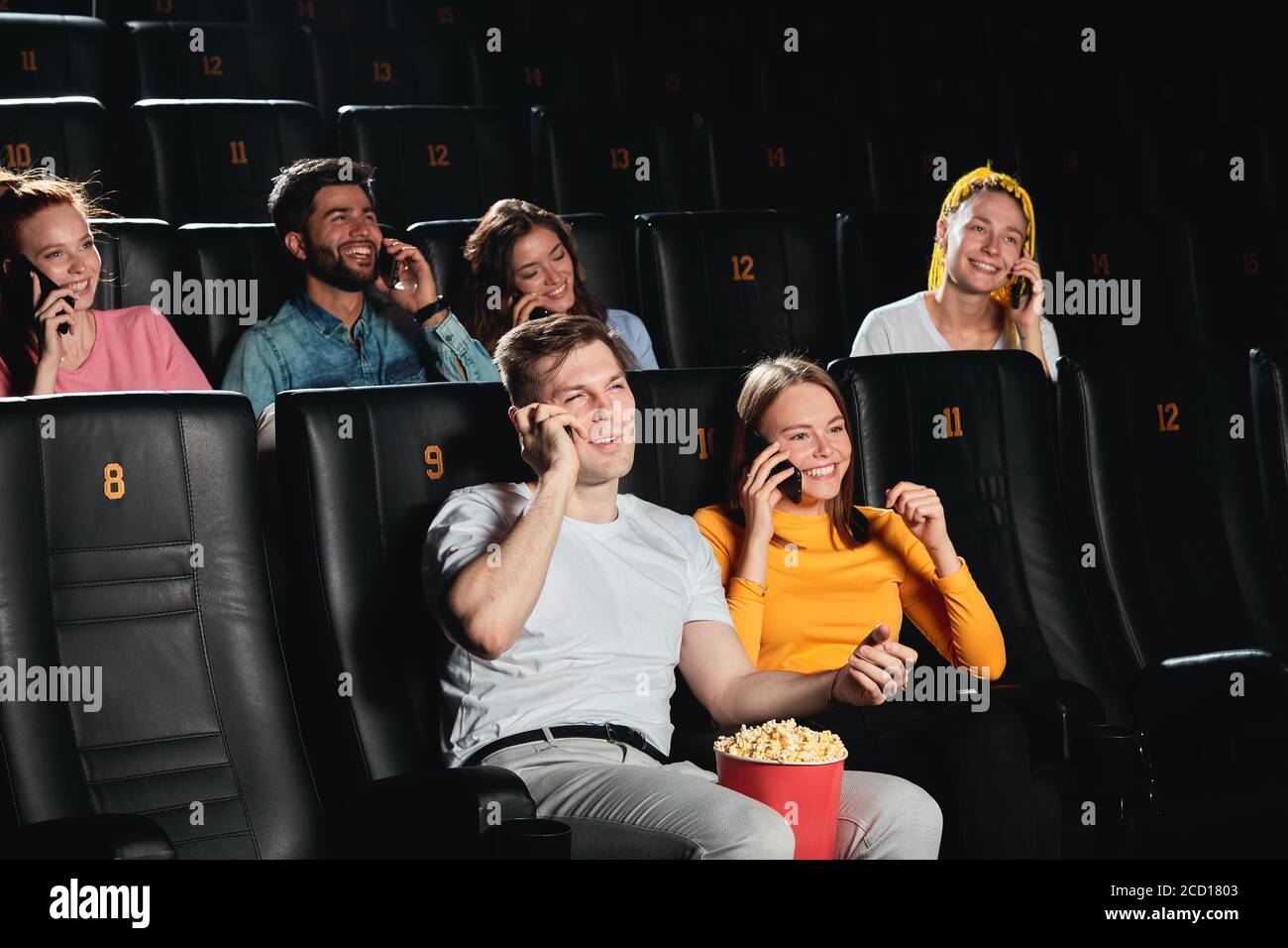 funny young people talking by phone and laughing while sitting at the ...