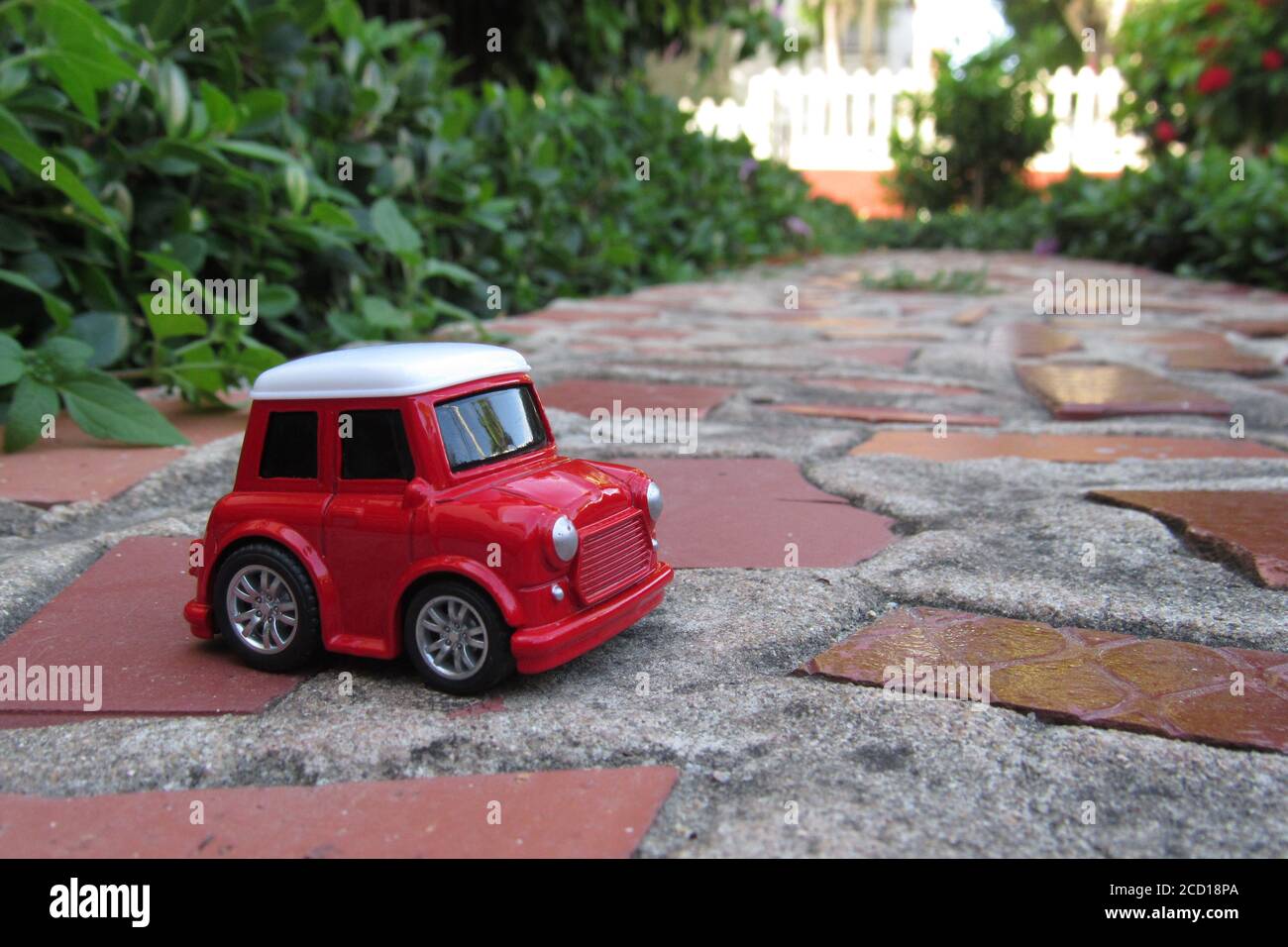 Closeup of a red car toy on the ground in a garden under the sunlight ...
