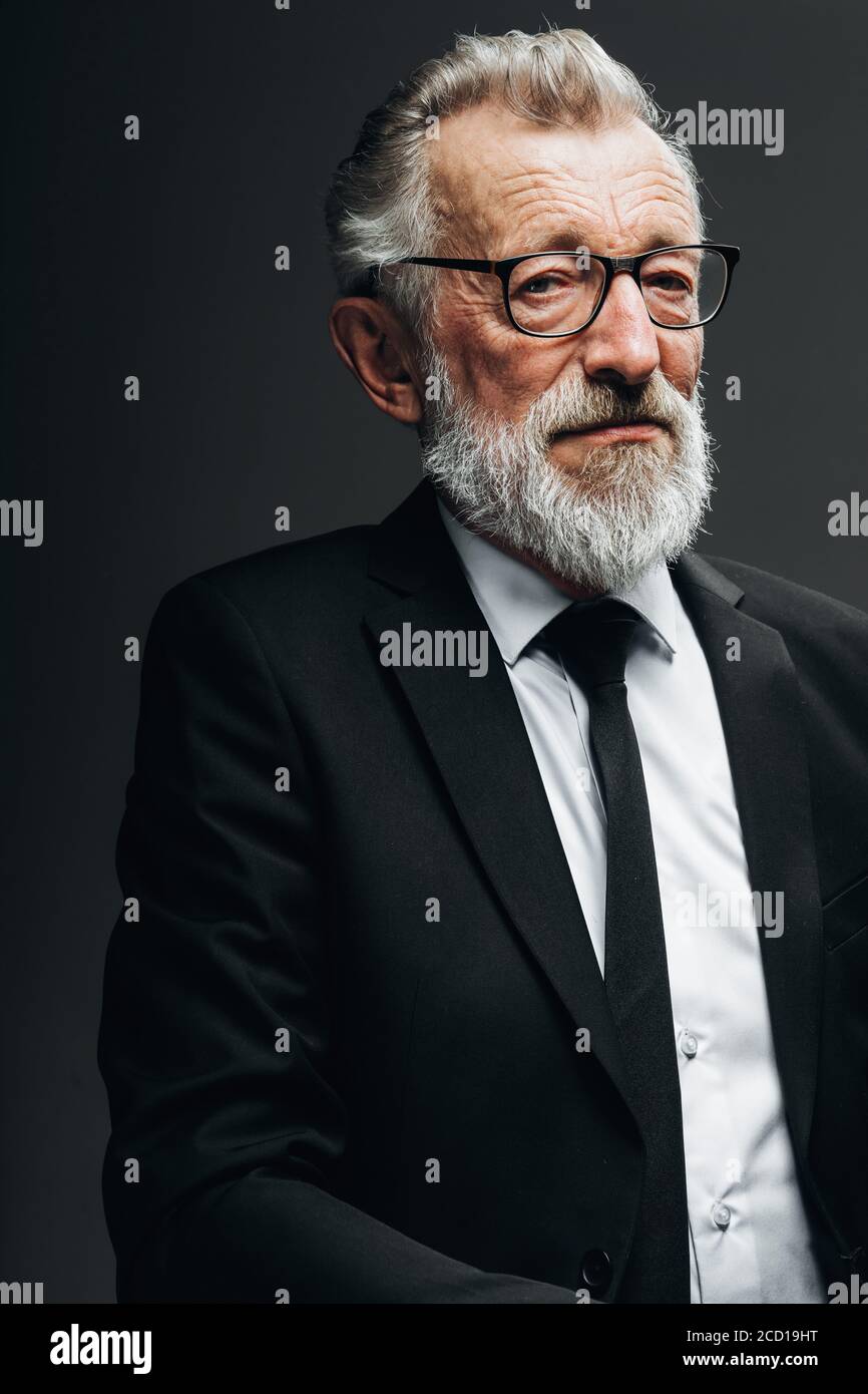 Portrait of handsome elderly CEO posing in black formal suit on dark ...