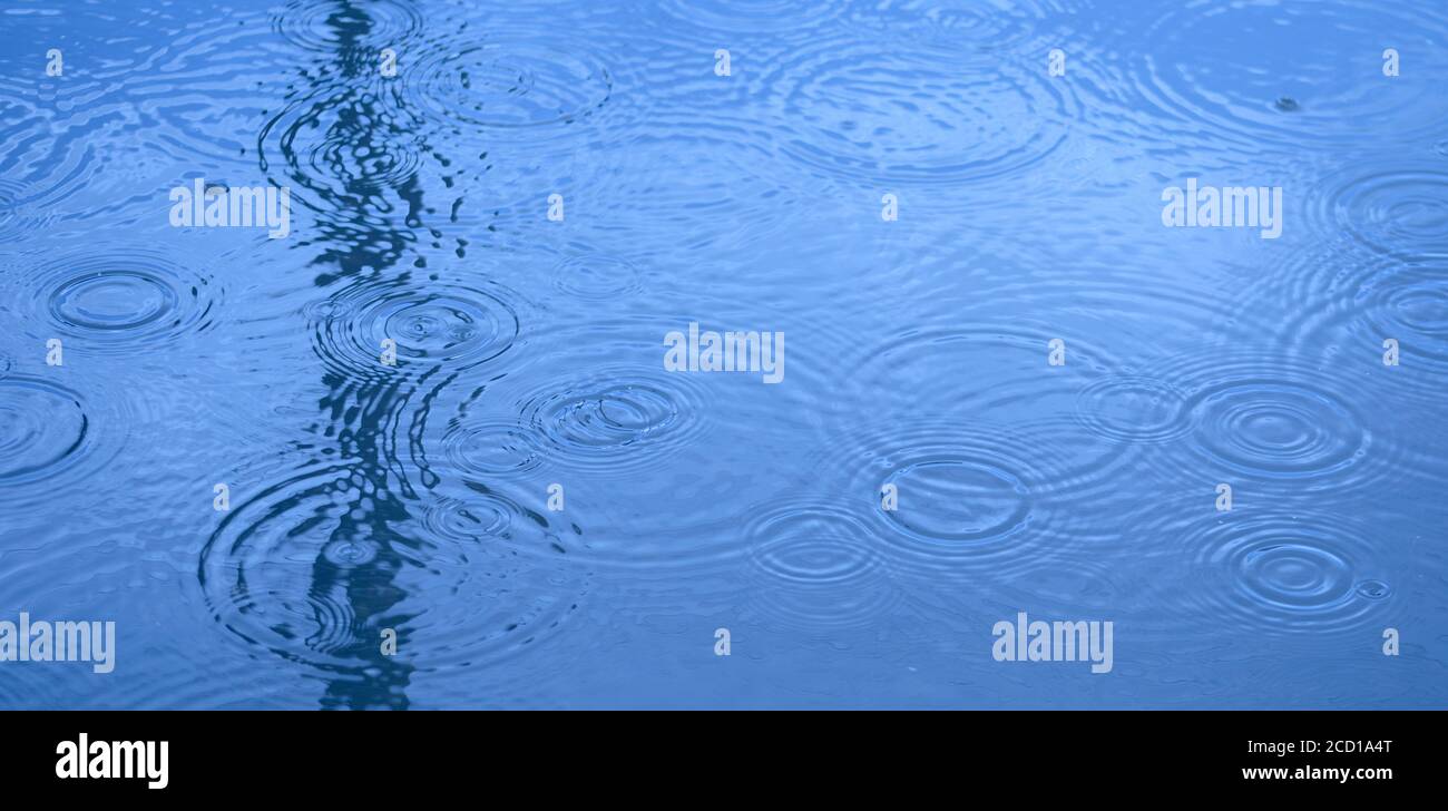 Sky reflection in water. Raindrops fall into a puddle Stock Photo - Alamy