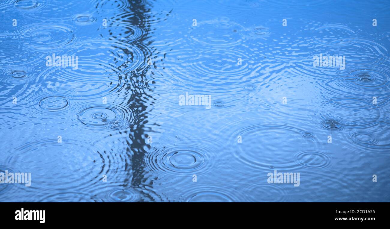 Sky reflection in water. Raindrops fall into a puddle Stock Photo - Alamy
