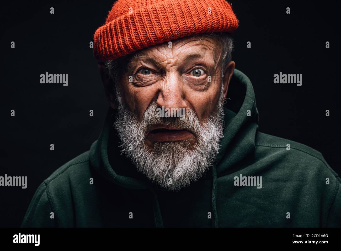 Portrait of old weird bum in orange hat with crazy eyes and puzzled ...