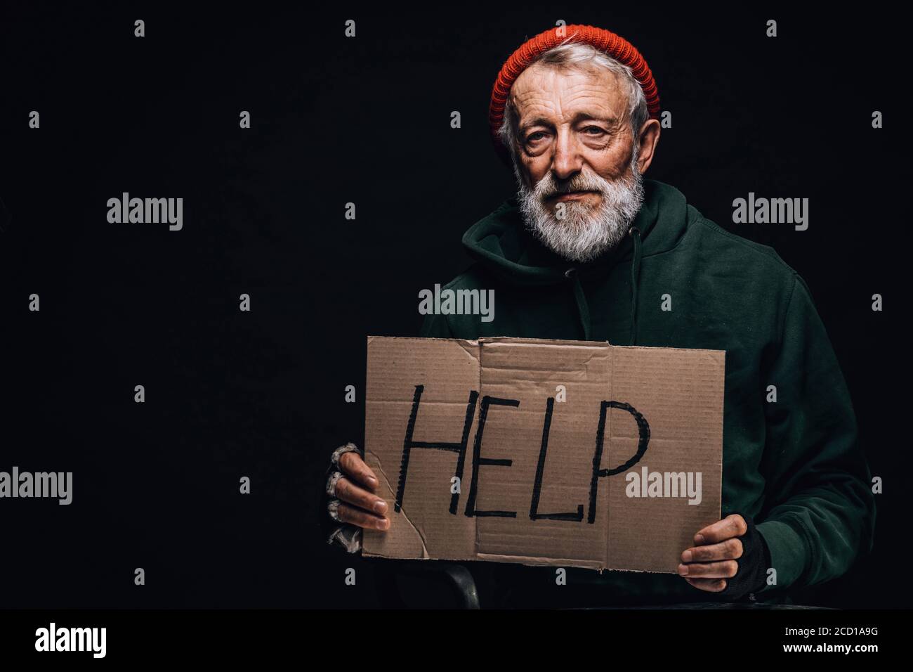 Sad exhausted old-aged bum in red hat and street wear holding a ...