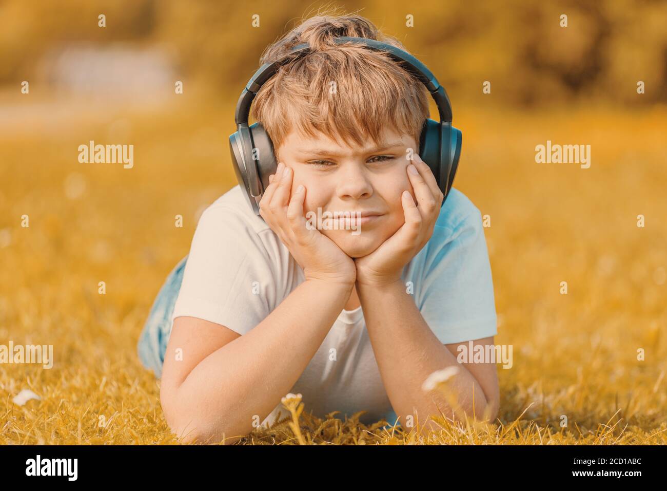 handsome boy with headphones listening to music lying on the grass ...