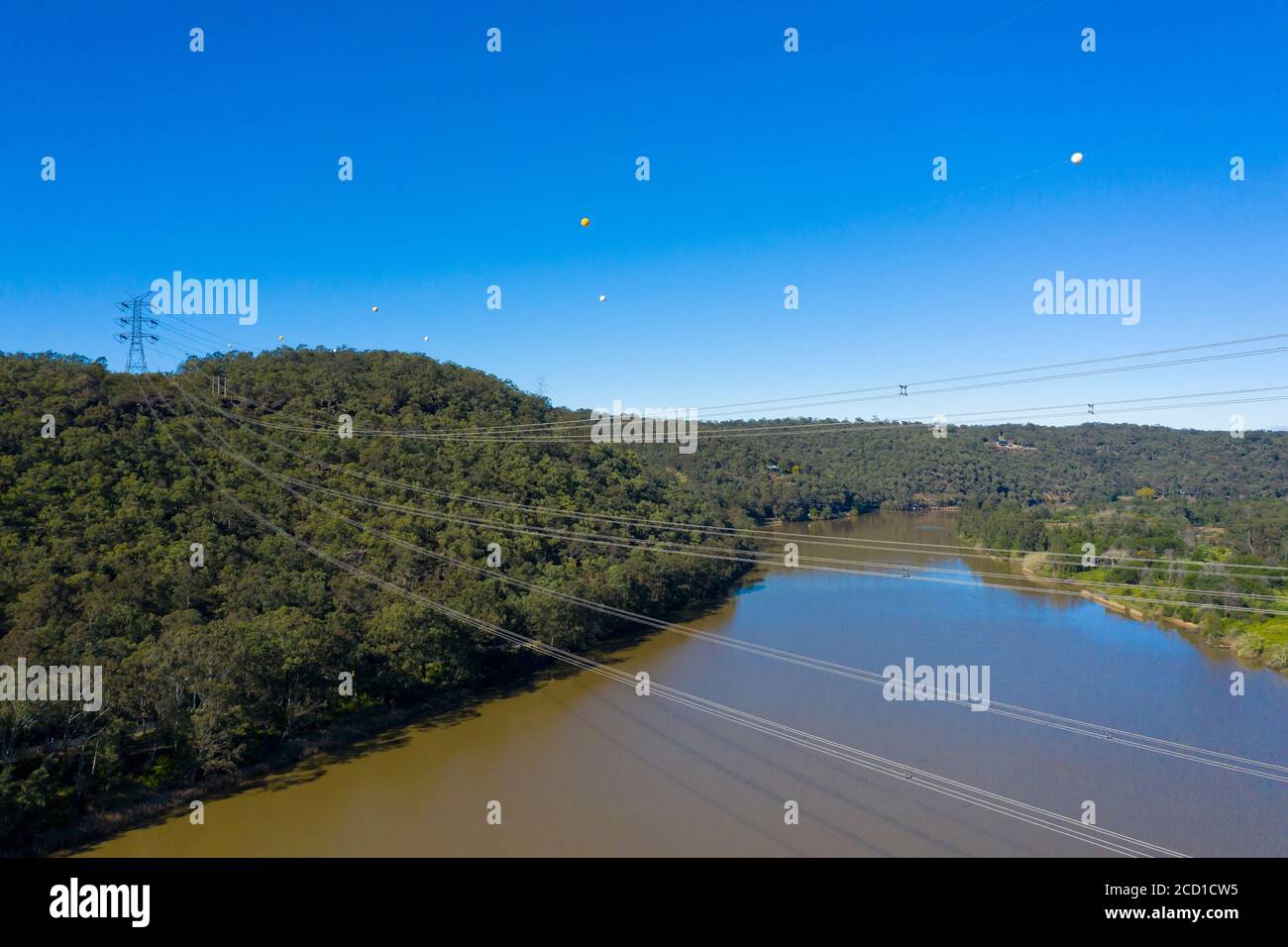 An electricity transmission tower and cables across a river in regional ...
