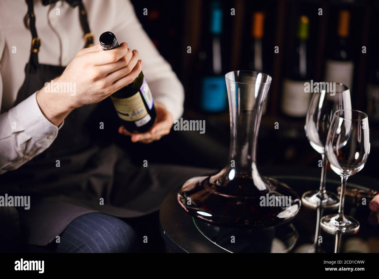 Close up of elegant sommeliers in white shirt and apron pouring wine in ...