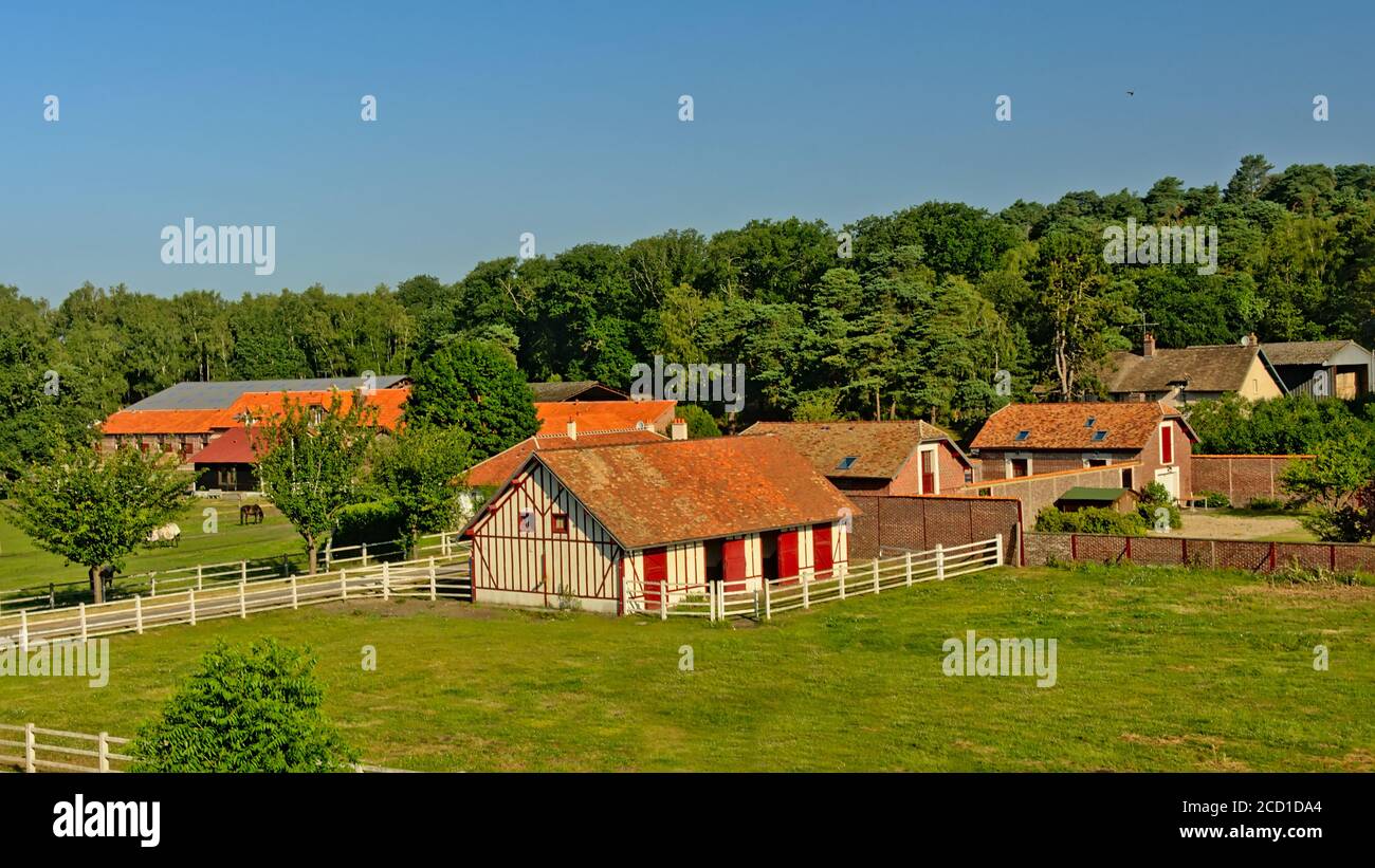 Horse stables in traditional brick stone style and meadows on a sunny ...