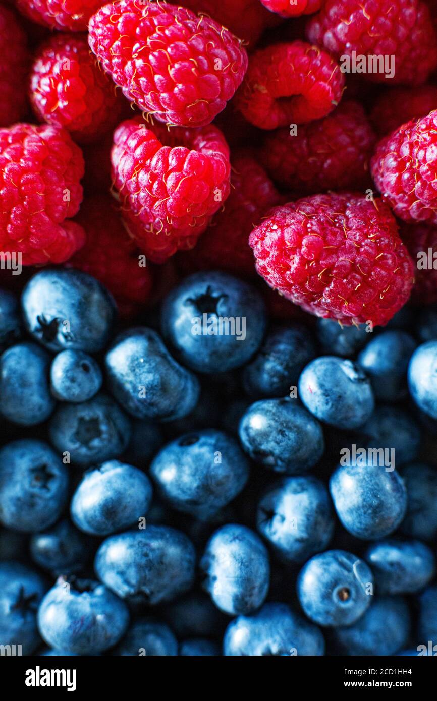 A close-up of raspberries and black blueberry split the frame. Summer ...