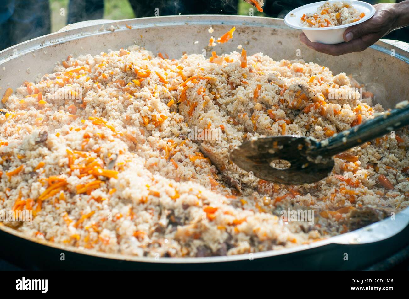 Cooking Uzbek pilaf. National food. Roasting meat in a large cauldron ...