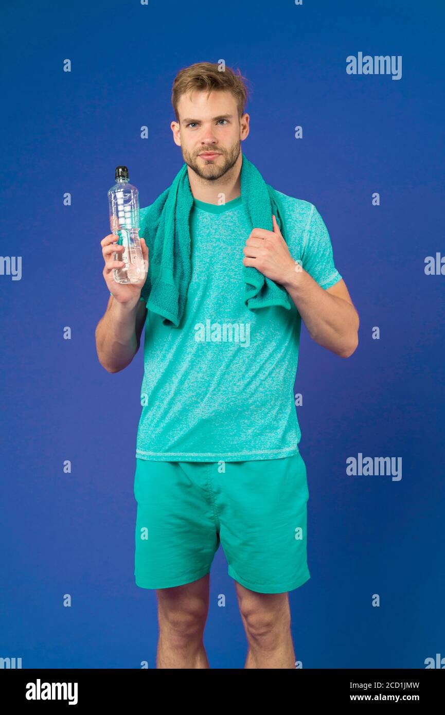 Stay hydrated. Man with towel on shoulders hold bottle. Athlete drink ...