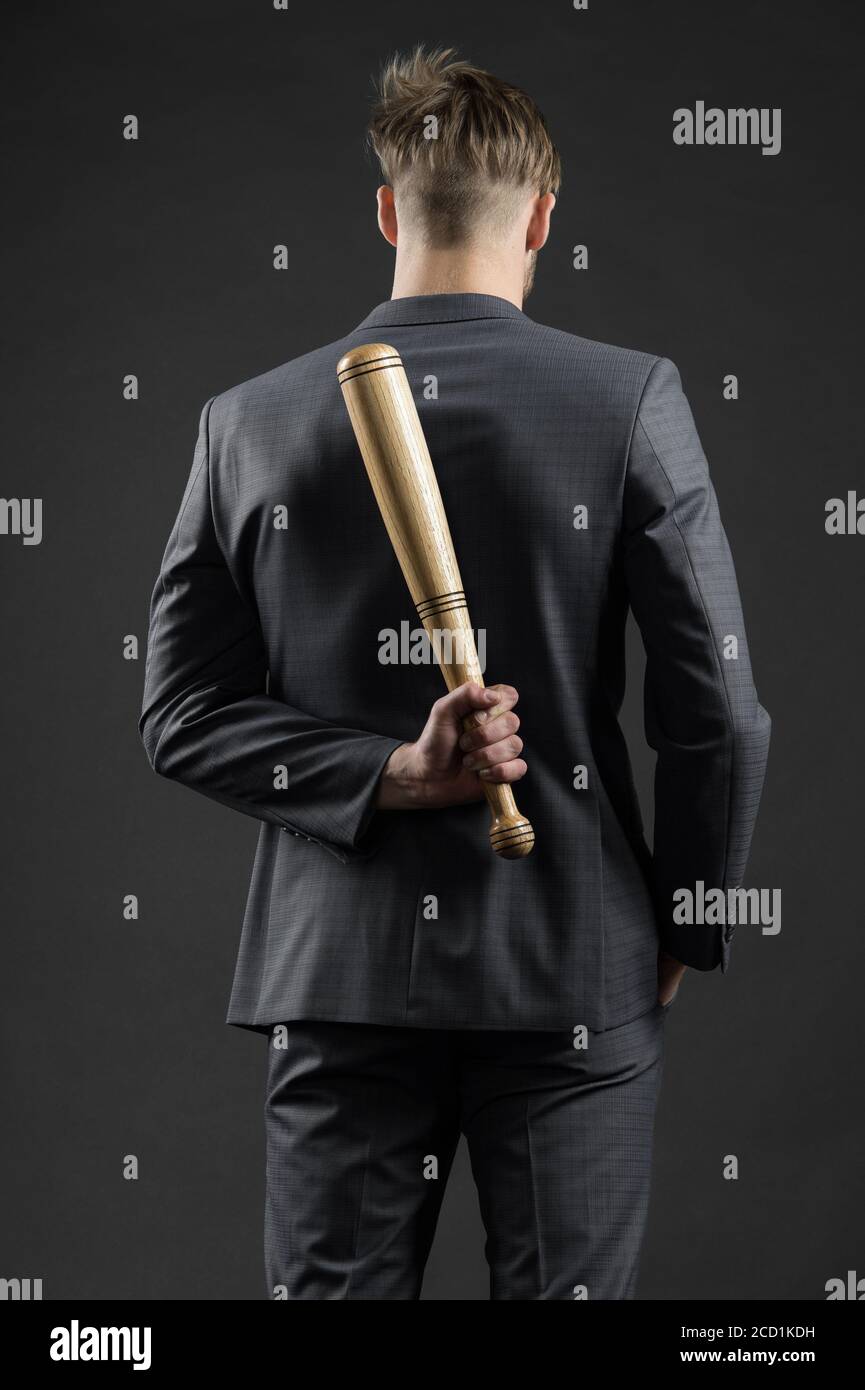 Latent aggression. Businessman or man in formal suit hides wooden bat ...