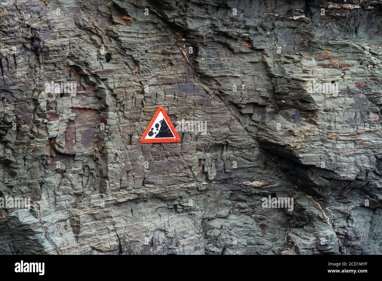Sign warning of falling rocks from a cliff face due to erosion Stock ...