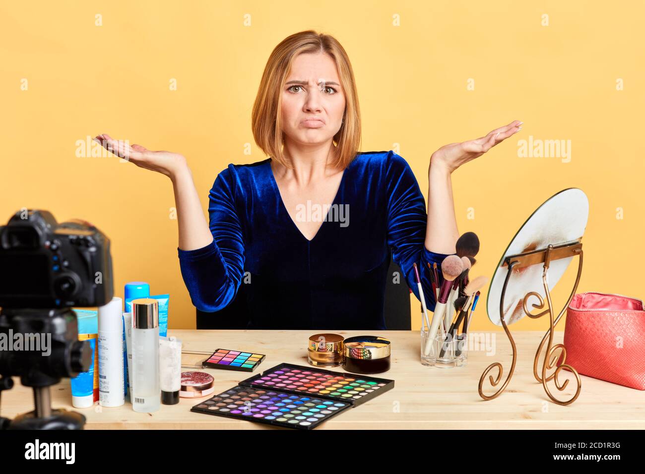 Dissatisfied clueless female TV presenter sitting at makeup table in ...