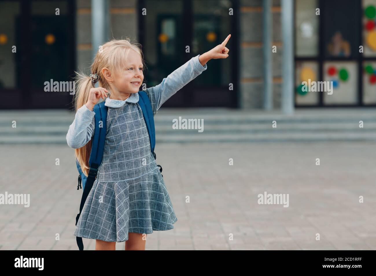 Cute little girl with backpack going back to school and pointing way ...