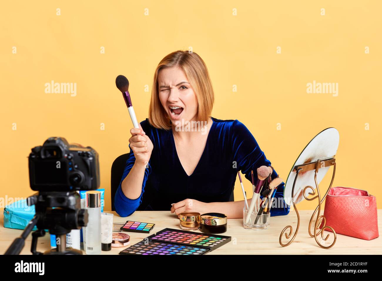 Famous successful young female vlogger with blonde hair winks at camera ...