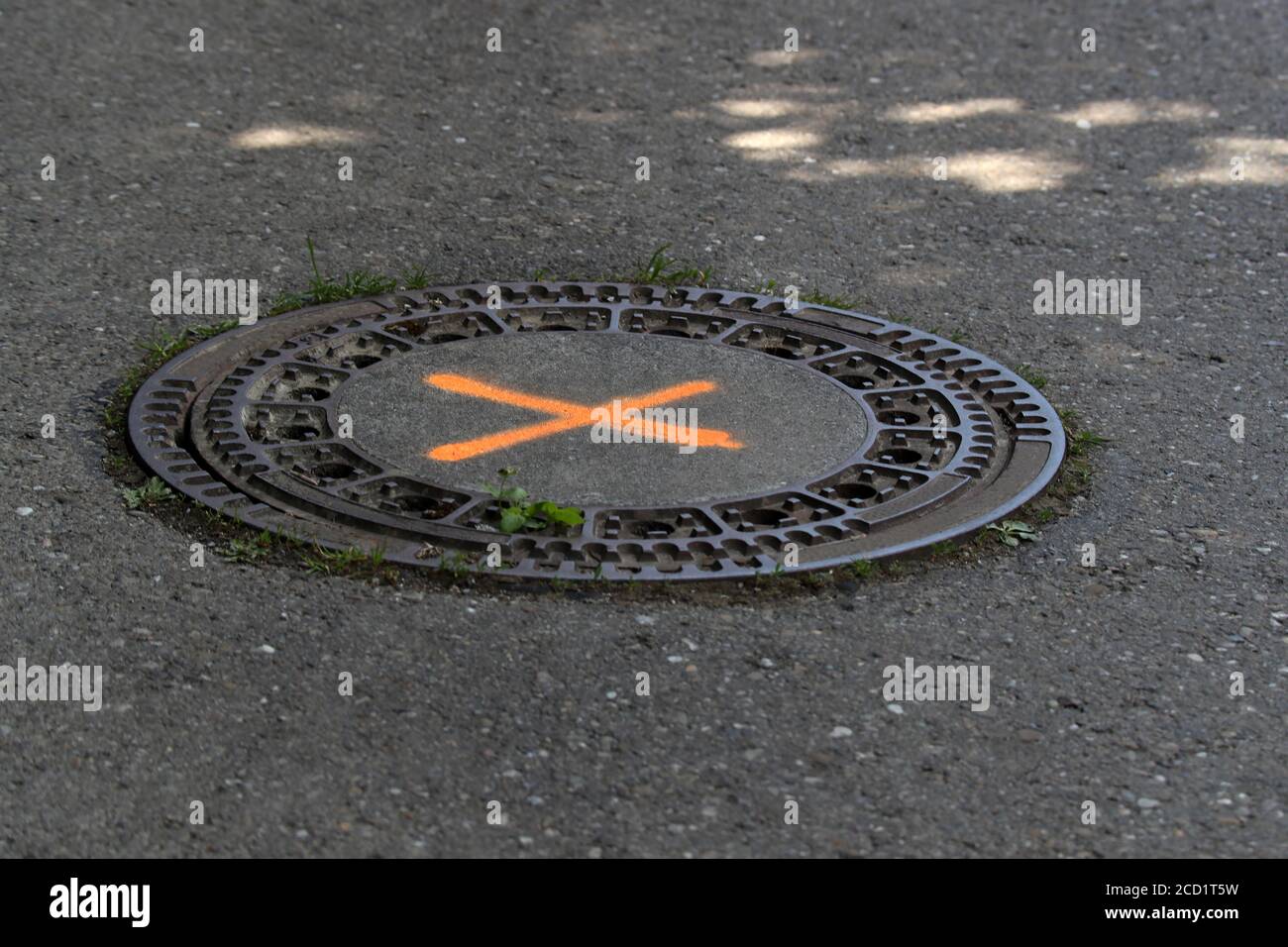 Round steel manhole on the road marked with a cross Stock Photo - Alamy