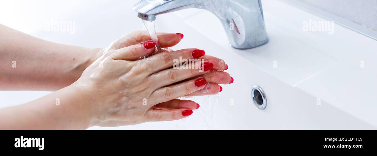 Washing hands in a public restroom (focus on the tap, hands in motion ...