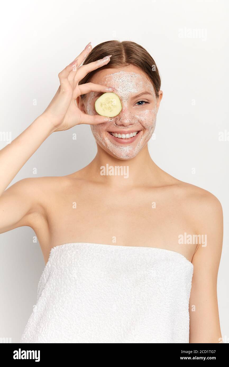 cheerful attractive girl having fun with a cucumber at spa salon ...