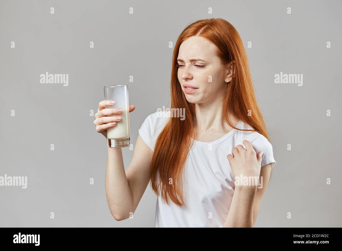 Little unhappy girl with a glass of milk isolated on white background ...