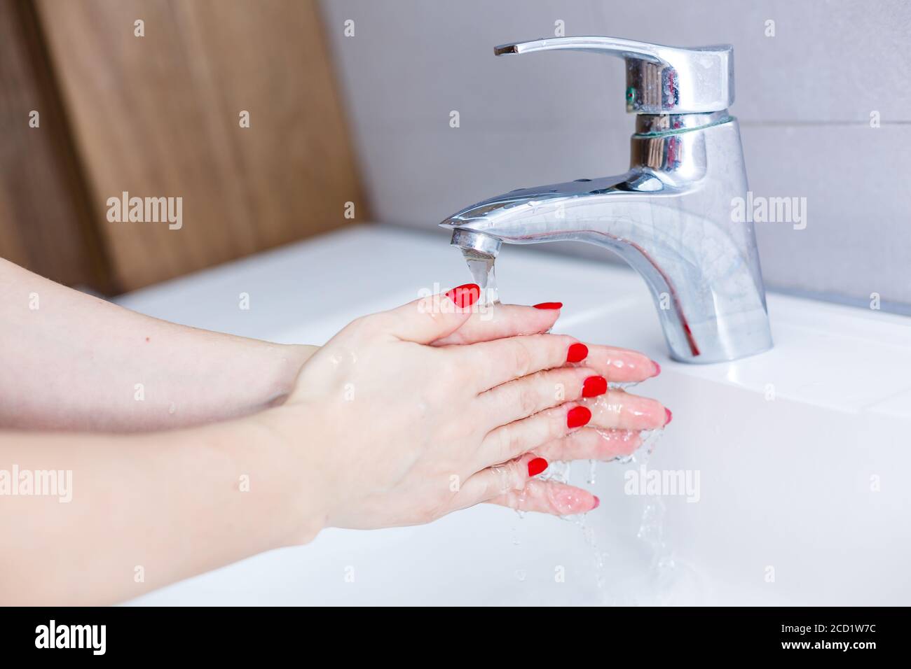 Washing hands in a public restroom (focus on the tap, hands in motion ...