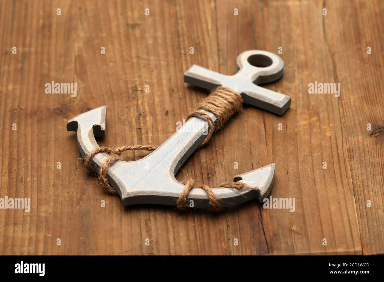 Miniature anchor lying on wooden background Stock Photo - Alamy
