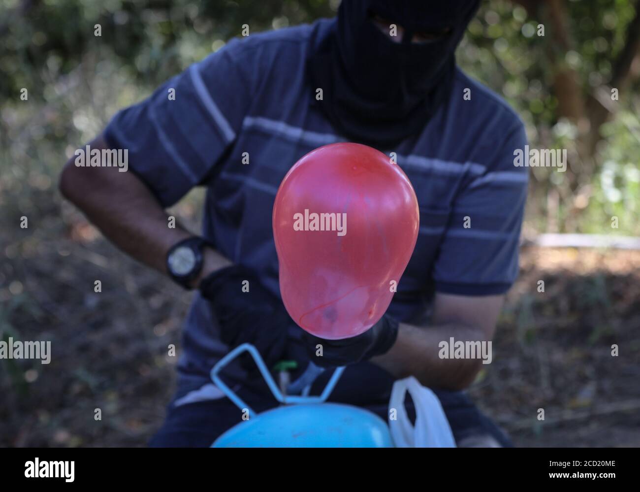 Masked Palestinian attaching incendiary devices to balloons before ...