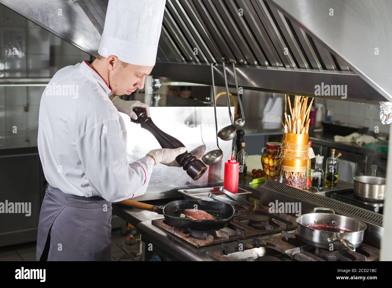 Chef in restaurant kitchen at stove with pan, cooking Stock Photo - Alamy