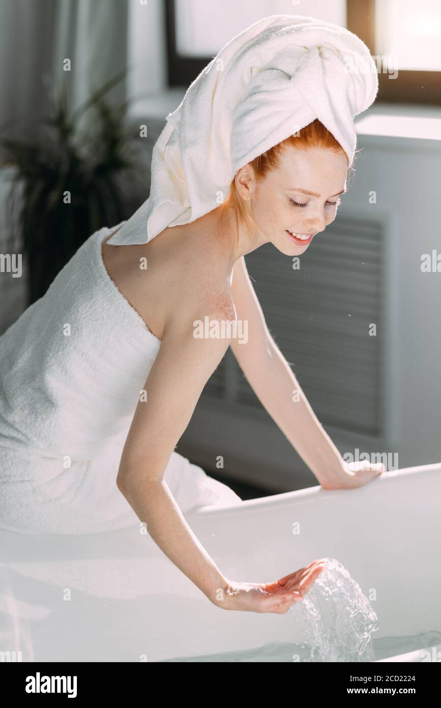 Morning routine of redhead beauty in the bathroom. Woman running bath ...