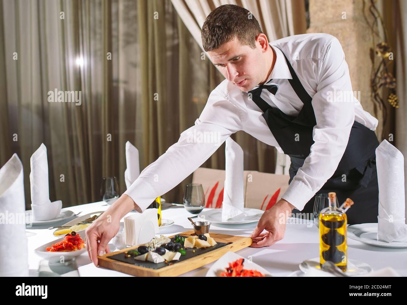 Waiter serving table in the restaurant preparing to receive guests ...