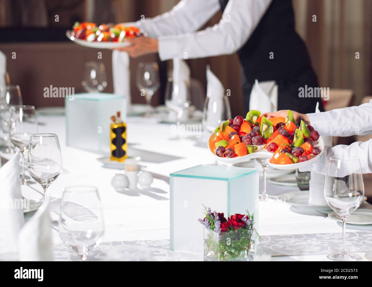 Waiters serving table in the restaurant preparing to receive guests ...