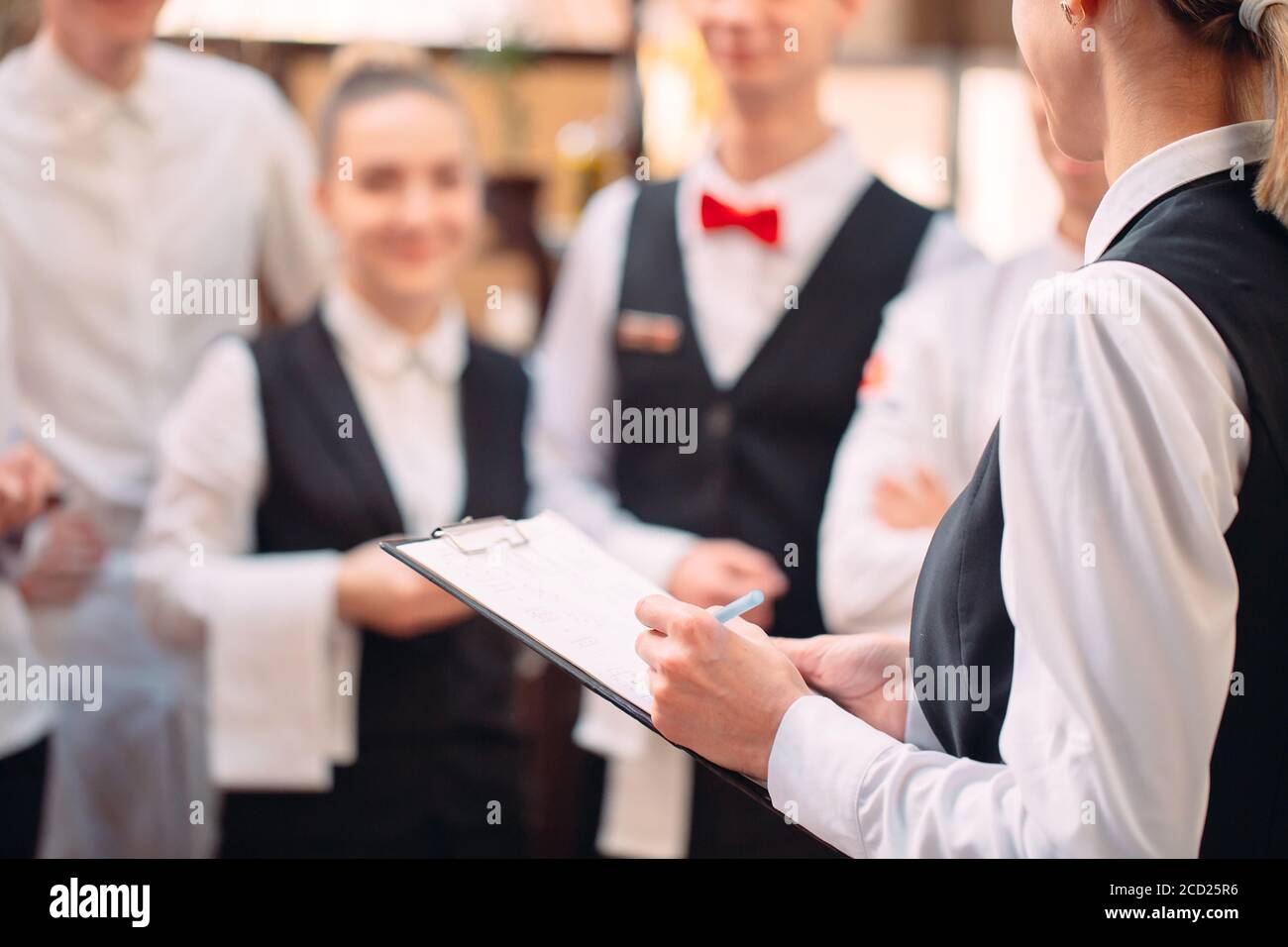 restaurant manager and his staff in kitchen. interacting to head chef ...