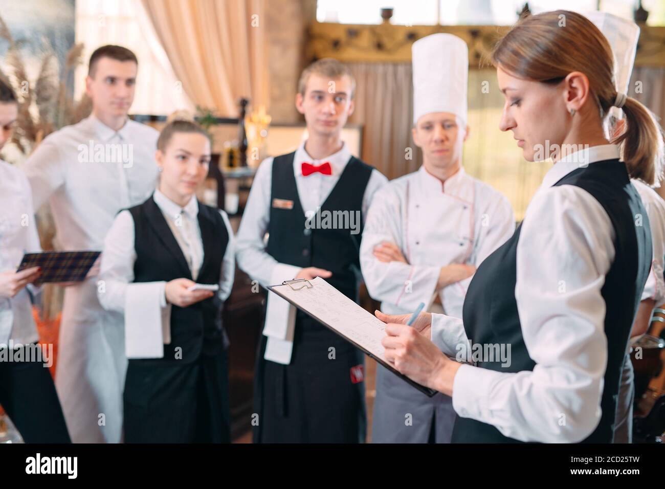 restaurant manager and his staff in kitchen. interacting to head chef ...