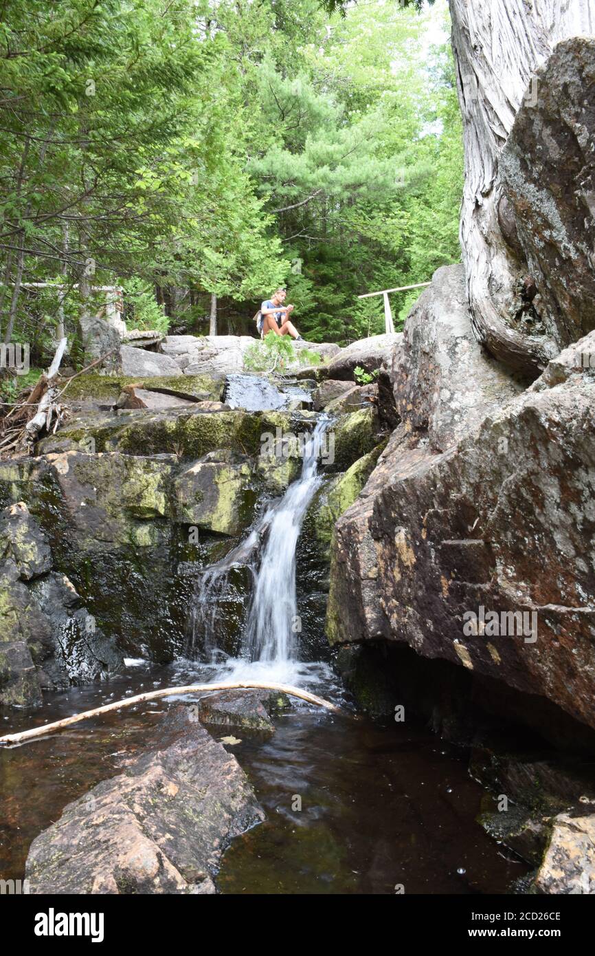 Girl sitting near a waterfall Stock Photo - Alamy