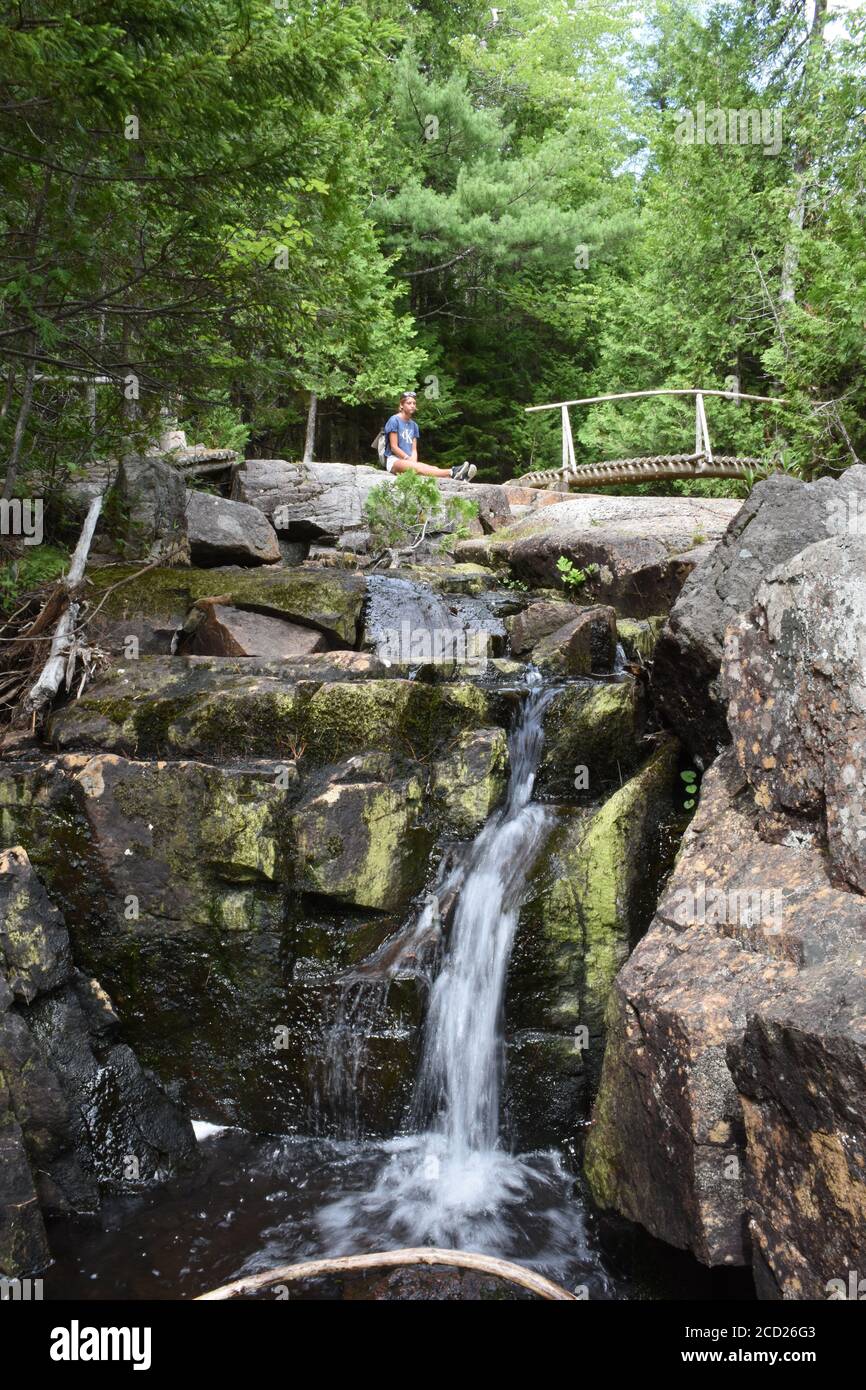 Girl sitting near a waterfall Stock Photo - Alamy