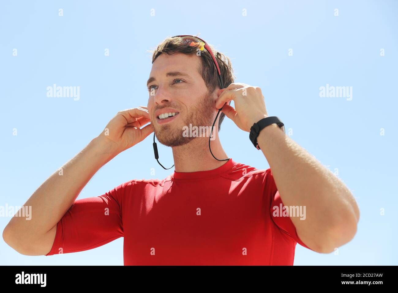 Runner man getting ready for run putting on wireless earphones with ...