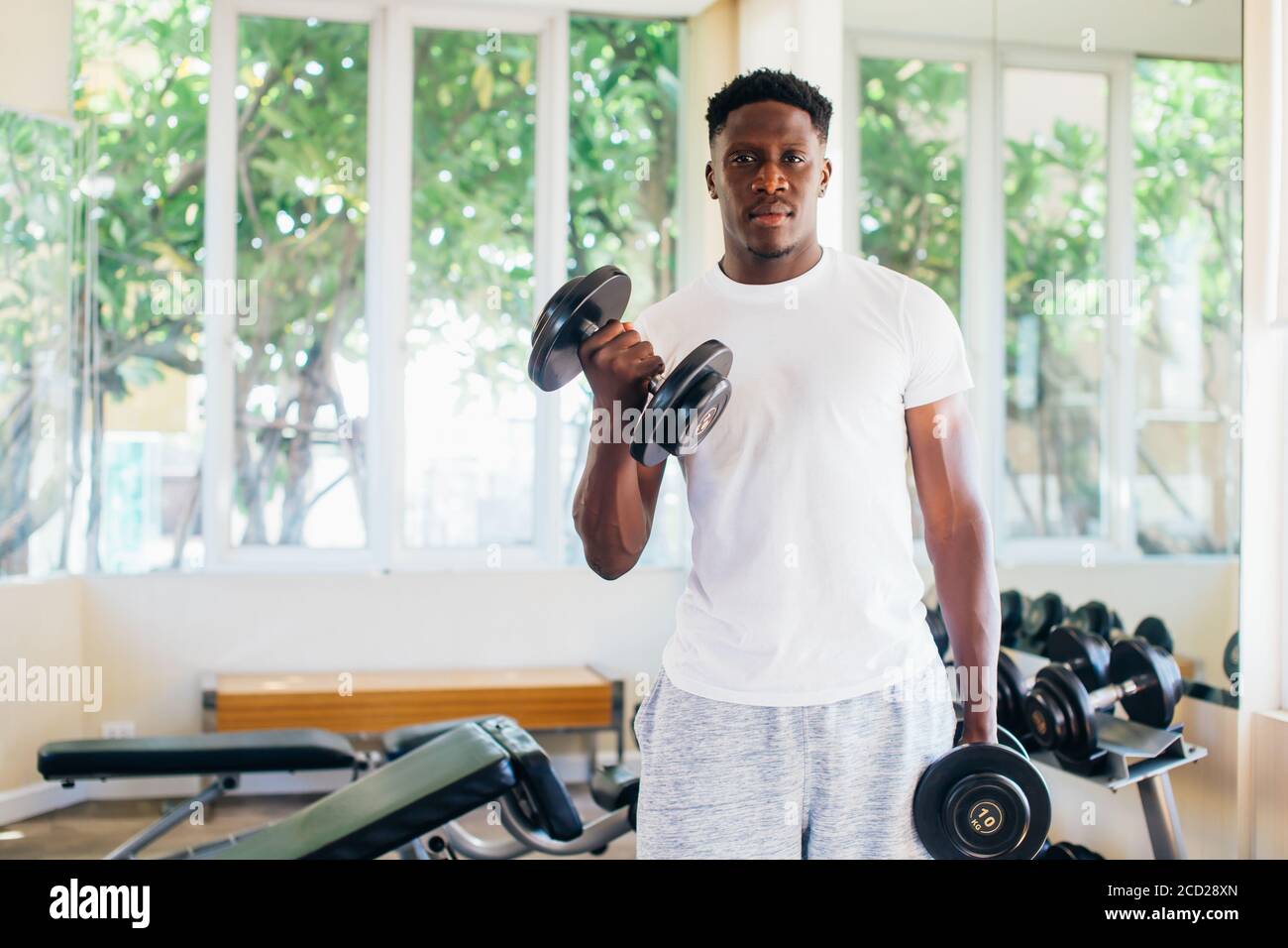 Young African American man standing and lifting a dumbbell with the ...